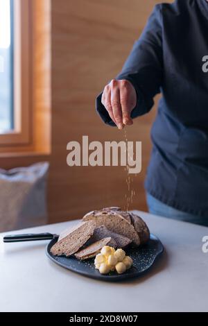 Sprinkling seasoning with chef's hands over metal trays in commercial ...