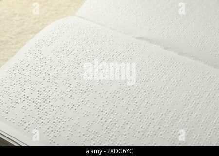 Book with Braille text on beige textured table, top view. Education and ...