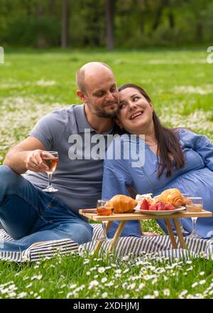 Cheerful Caucasian couple on maternity shoot in a sunflower field ...