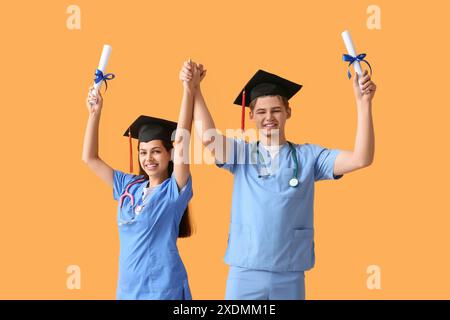 Happy medical graduate couple with diplomas and stethoscopes giving ...