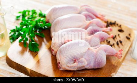 Quail carcasses lie on cutting board. Small birds are prepared for ...
