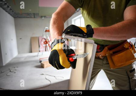 Construction worker carefully cutting drywall using a utility knife ...