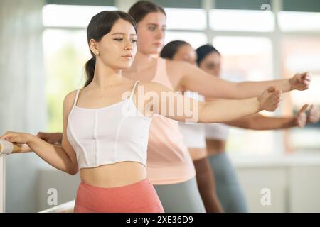 Young girl practicing second arm position holding by ballet barre Stock ...