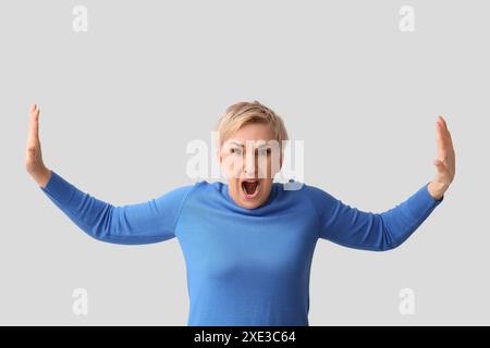 Scared mature woman on light blue background Stock Photo - Alamy