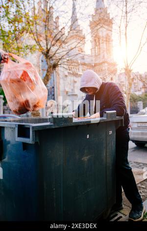 Homeless man looking into trash box in search for food on church ...