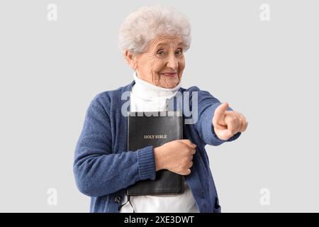 People pointing at senior woman with Holy Bible on green background ...