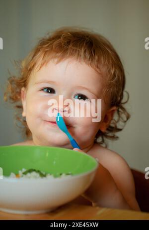 Cutr baby child eating himself with a spoon Stock Photo - Alamy