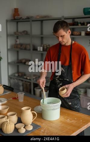 Close Up Of Potter Applying Glaze To Clay Plate In Ceramics Studio ...