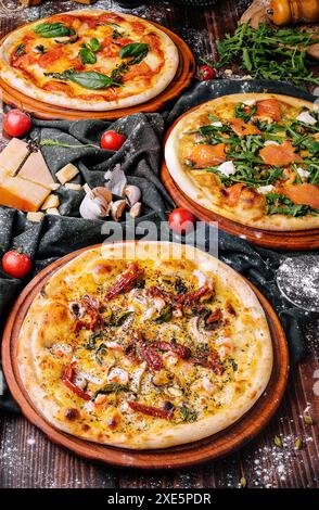 Three different pizzas on wooden background with tomato sauce, mixed ...