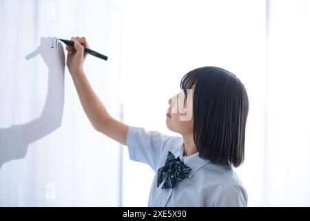Student writing answers on whiteboard Stock Photo - Alamy