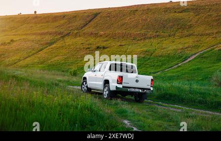 white Volkswagen Amarok near green hill. Rear view of double cab VW ...