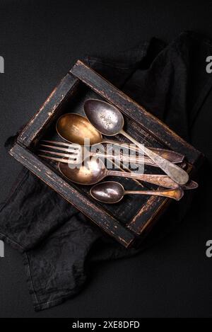 vintage metal empty spoons on black graphite background, top view, copy ...