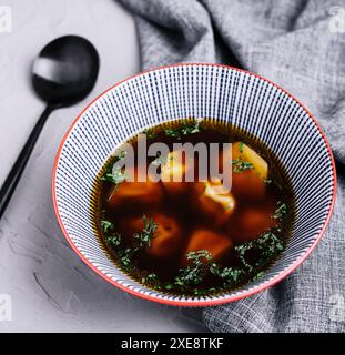 Bowl of tasty dumpling soup and green onion on color background Stock ...