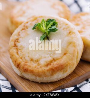 Board with tasty cottage cheese pancakes and sauce on table, closeup ...