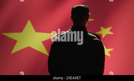 Member of chinese army doing saluting hand gesture towards China flag ...