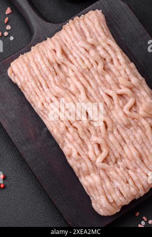 Fresh minced chicken with salt, spices and herbs on a wooden cutting ...