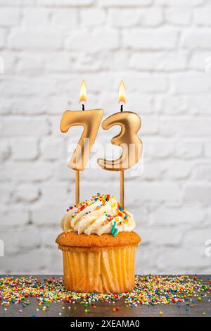 Birthday number 73 - Golden candle with cupcake Stock Photo - Alamy