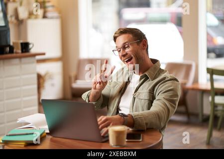 Handsome smiling man shows peace, v-sign near face and looks positive ...