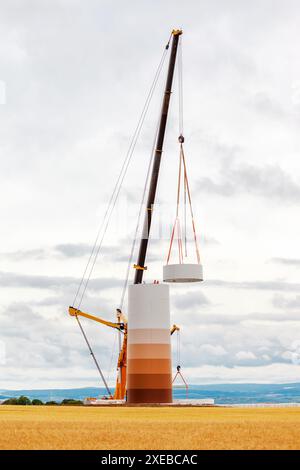 Building and assembling a construction windmill by crane. Farmland with ...