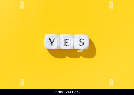 Yes word on white cube blocks isolated on yellow background Stock Photo ...