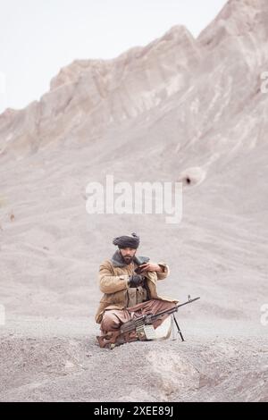 A Taliban soldier with a machine gun, In the desert mountain landscape ...