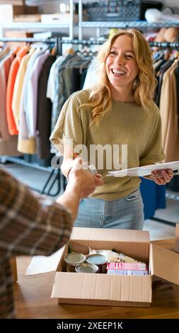 Female worker receiving clothes from client at modern dry-cleaner's ...