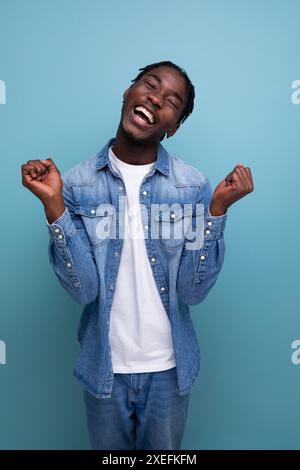 Pleasant looking curly man pointing finger aside at copy space, showing area for advertisement ...