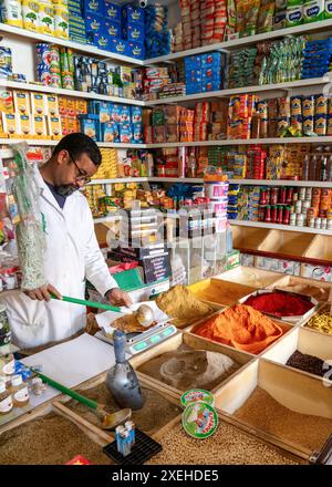 Er-Rich, Morocco - 7 March, 2024: Moroccan shopkeeper mixing spices in ...