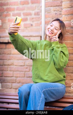 young Asian woman enjoying mobile gaming on smartphone while relaxing ...