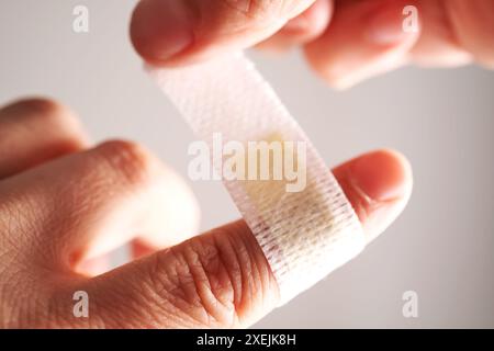 Applying an adhesive plaster to a finger. Close-up Stock Photo - Alamy