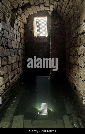 A dimly lit stone passageway leading to an ancient structure in Merida ...