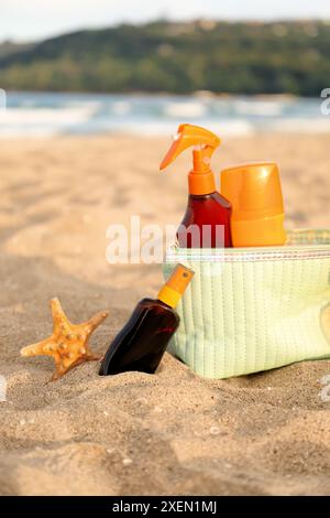 Bag with bottles of sunscreen cream on beige background with space for ...