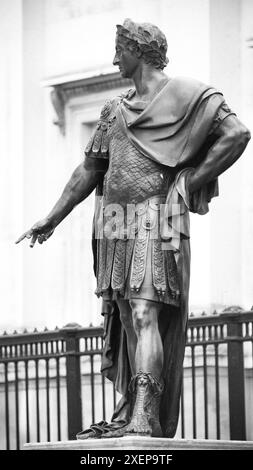 Metal statue of roman emperor standing in front of tower of medieval ...