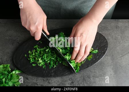 Woman cutting fresh coriander at grey textured table, top view Stock ...