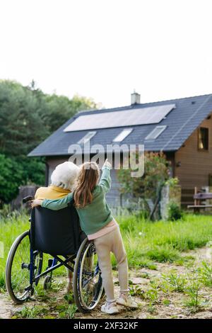 Granddaughter showing grandma solar panels on roof. Senior lady in ...