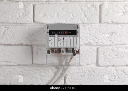 Electric meter on white brick wall. Energy measuring device Stock Photo ...