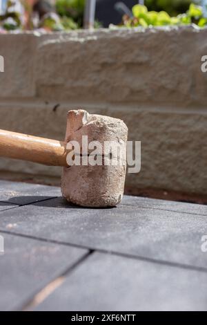 Man laying composite decking tile patio with a rubber mallet. Garden ...
