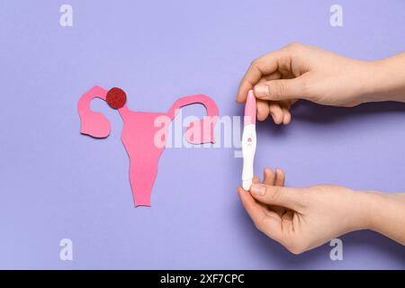 Female hands with paper uterus and pregnancy test on beige background ...