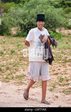 Basarwa african women walking on dirt road out of the village, San ...
