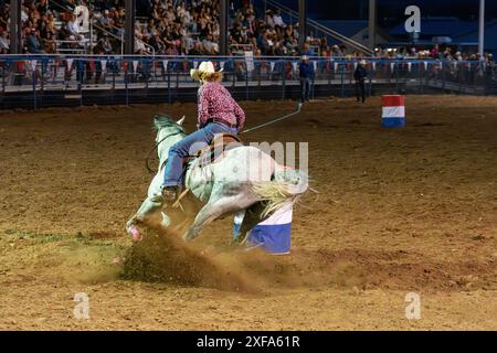 A cowgirl turns around the barrel while competing in the barrel racing ...