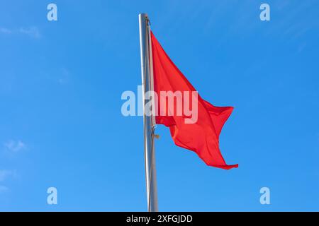 Chinese flag waving against a bright blue sky with soft white clouds ...
