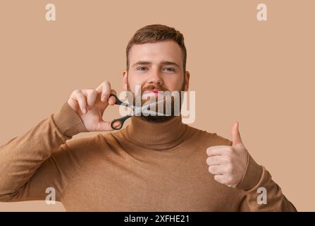 Young bearded man holding scissors on color background, closeup Stock ...