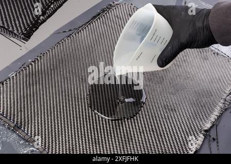 hand pouring epoxy resin on woven carbon fiber reinforcement cloth ...