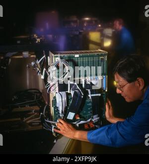 Technician testing electronic components and wiring inside disassembled ...