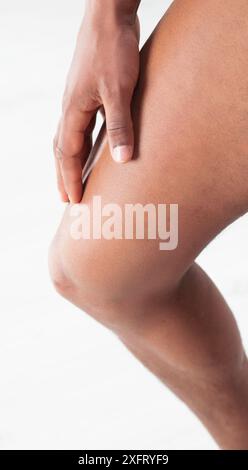 man is pressing his thigh with one hand, suggesting leg pain. His feet ...