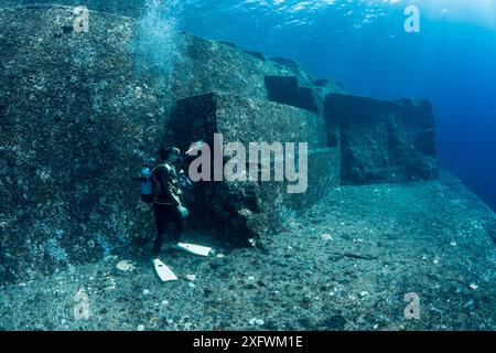 Scuba diver exploring the Yonaguni Monument, a submerged rock formation ...