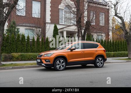 Samoa Orange SEAT Ateca parked near modern brick building. Three ...