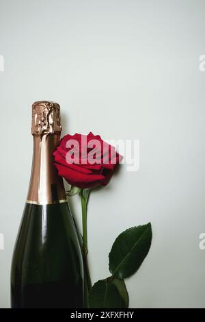 Vertical photo of bottle of champagne and luxurious red Colombian rose ...
