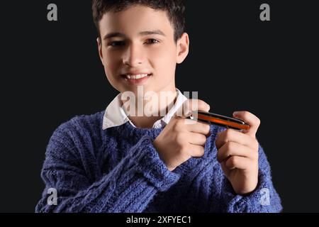 Teenage boy with harmonica on black background, closeup Stock Photo - Alamy