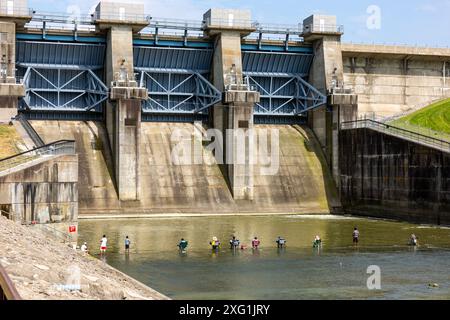 Fishermen sit in the water below the spillway of the J. Edward Roush ...